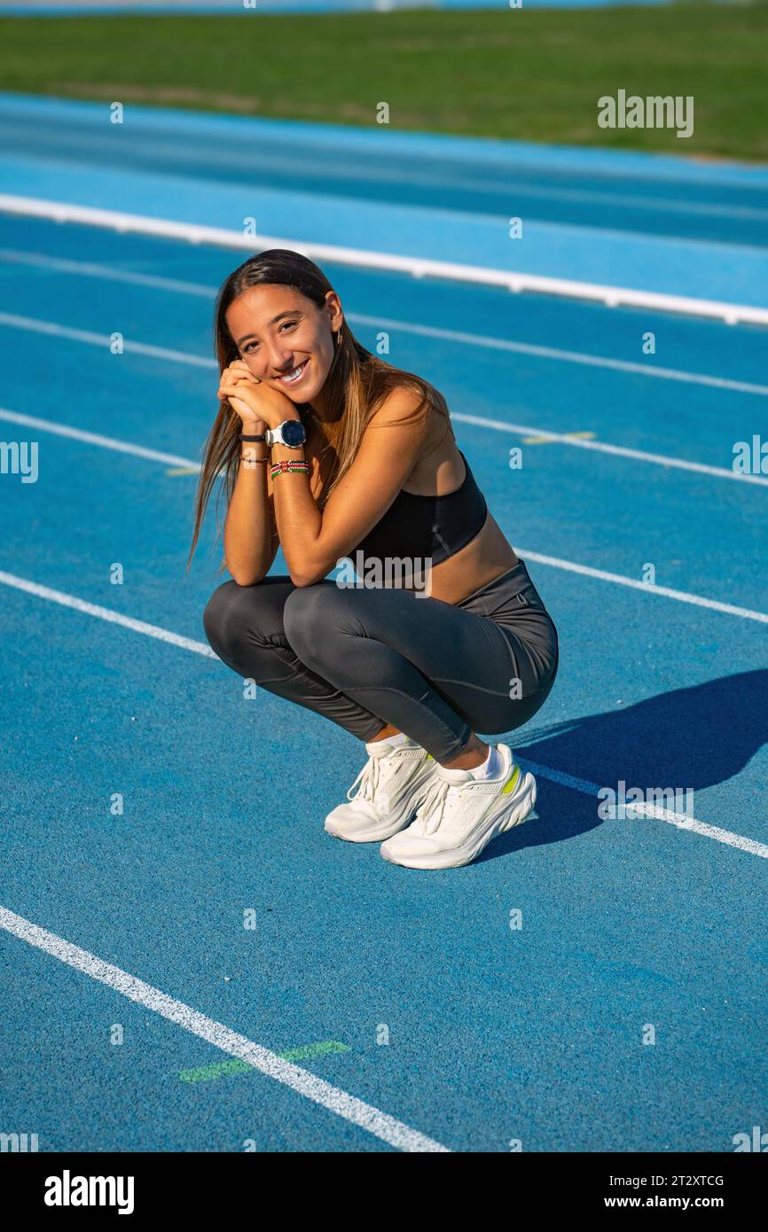 A beautiful young runner, tanned with her long brown hair, sitting ...