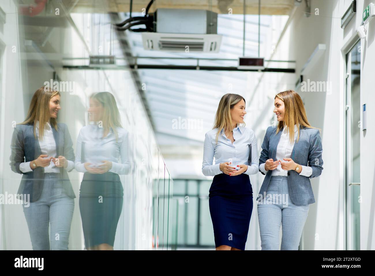 Two pretty young business women walking and discussing in the office ...