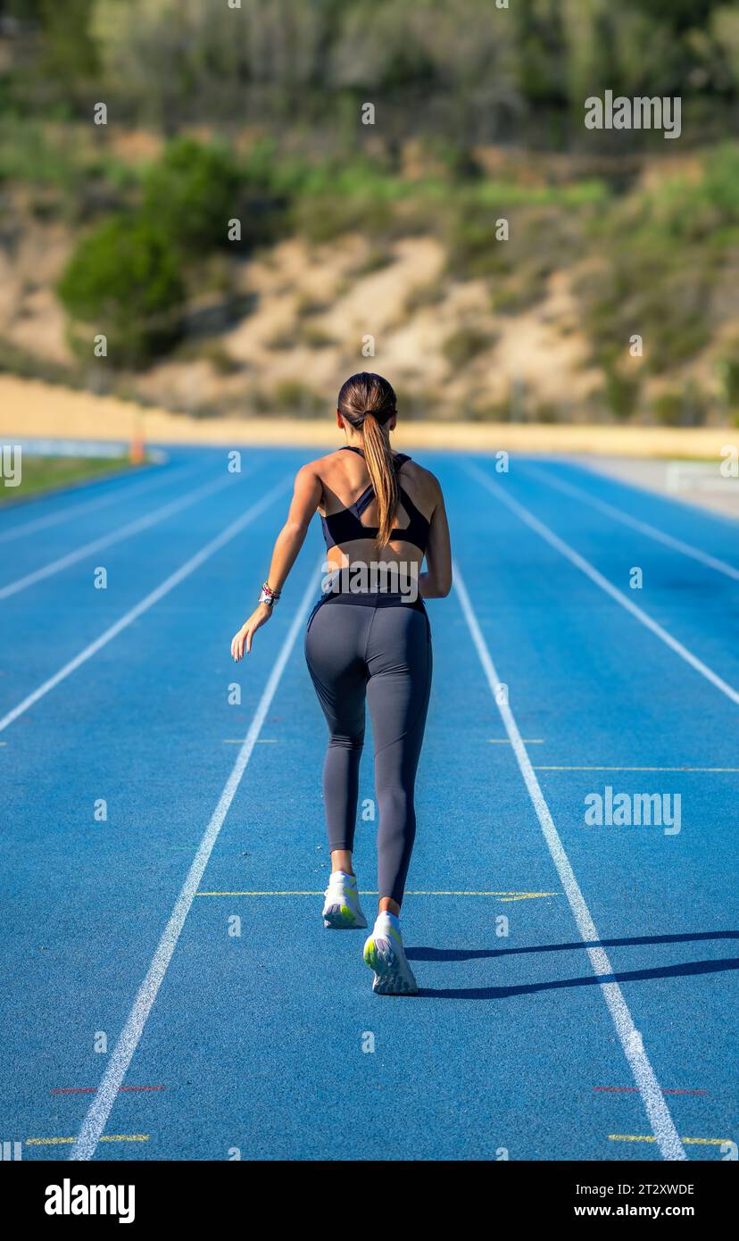 Beautiful tanned young slim runner girl, dressed in tight sportswear ...