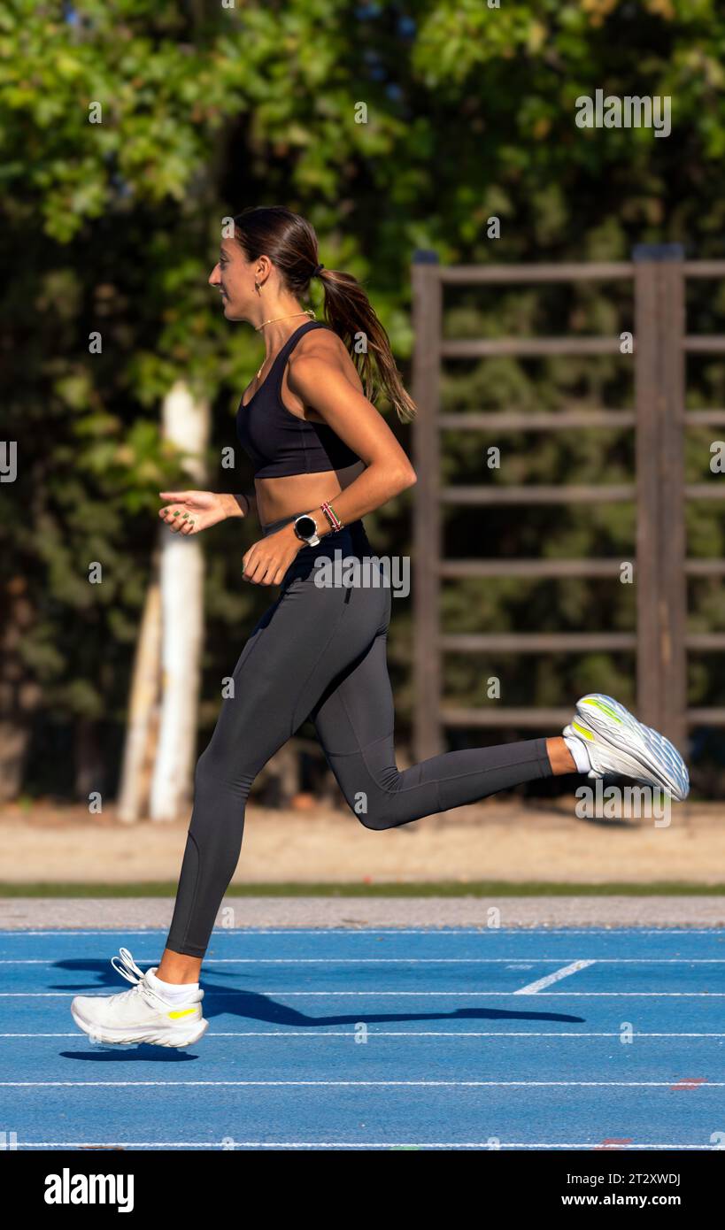 Beautiful young slim tanned runner girl, dressed in tight sportswear ...