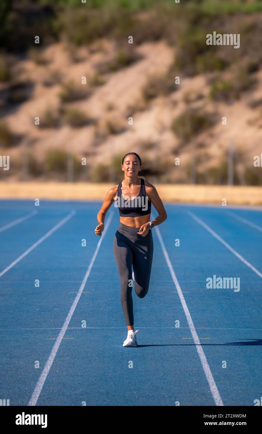 Beautiful slim tanned runner girl, dressed in tight sportswear, smiling ...