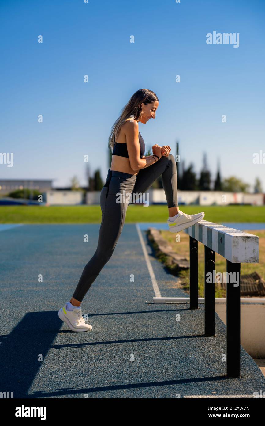 Beautiful young runner, tanned with long dark hair, smiling and flexing ...