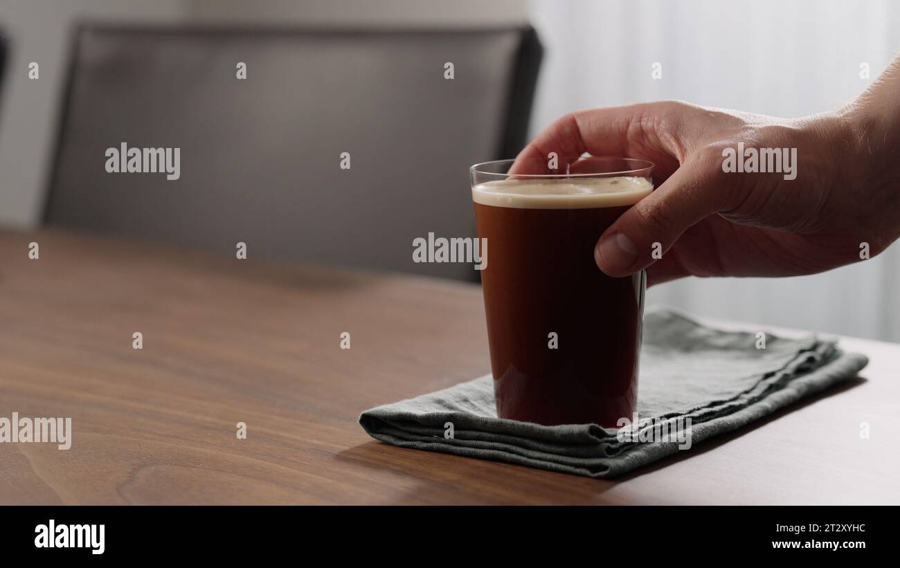 man hand take nitro coffee in thin glass on walnut table, wide photo ...