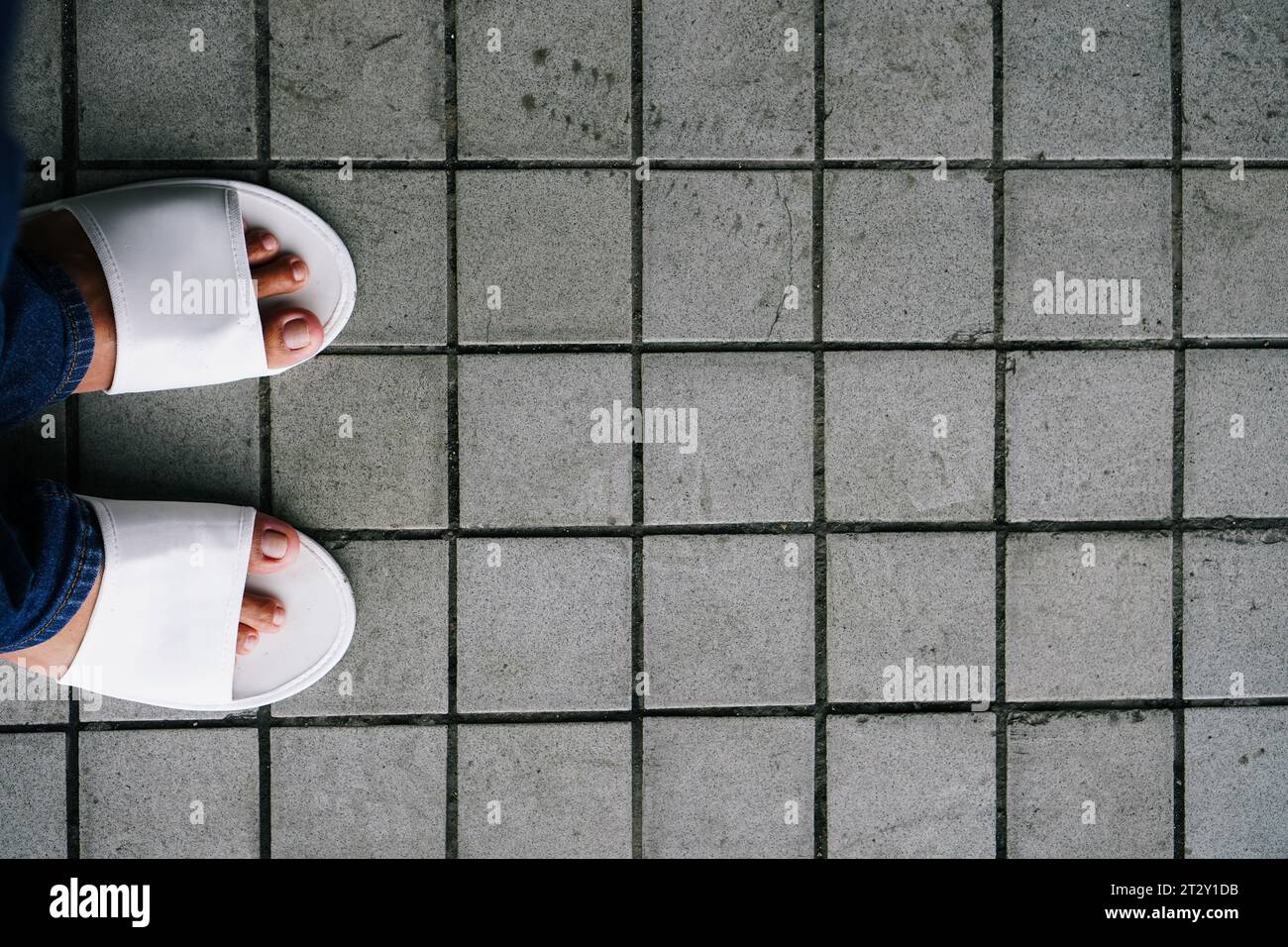 Focus on feet wearing white hotel sandals, positioned on a square ...