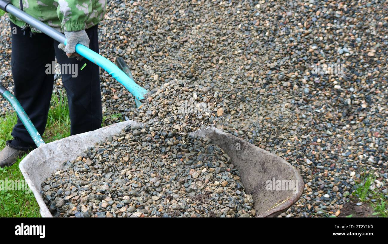 a man loads crushed stone from a large pile on the local area with a ...