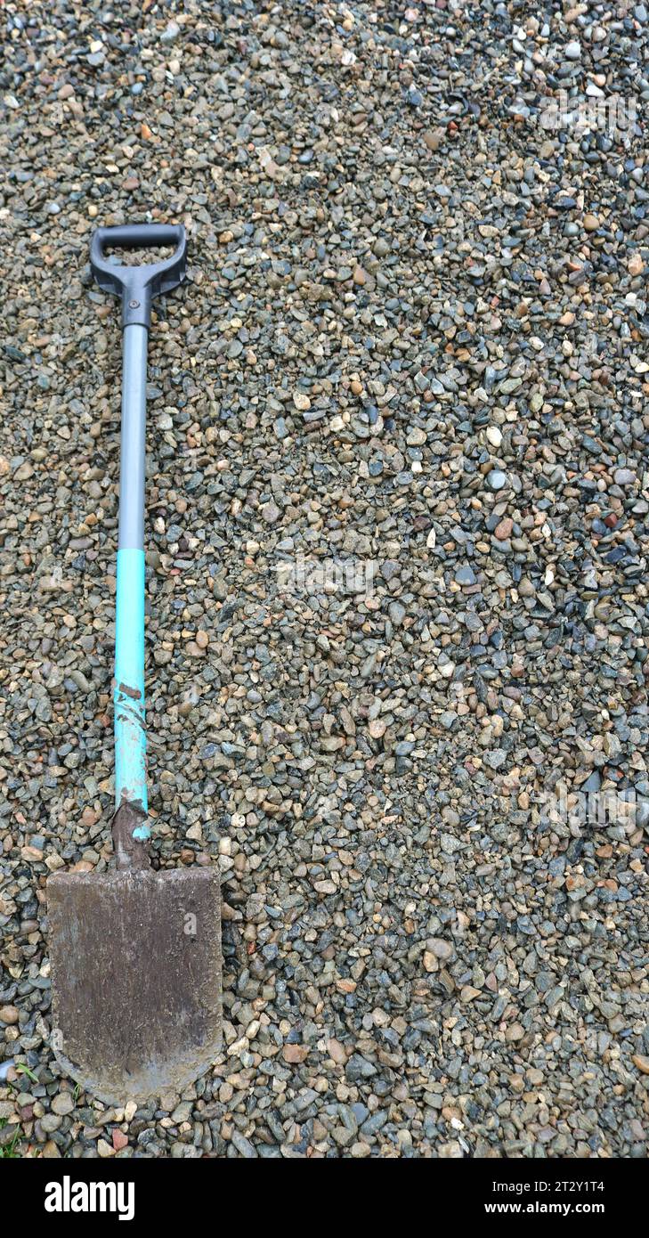 a shovel lying on a pile of fine gray gravel as a texture on the theme ...