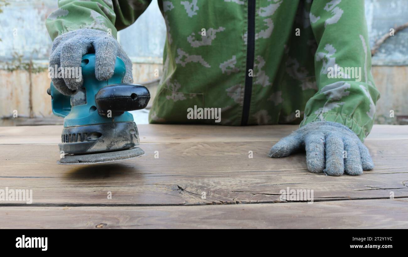wood craftsman sands solid wood using a sander, polishing oak boards to ...