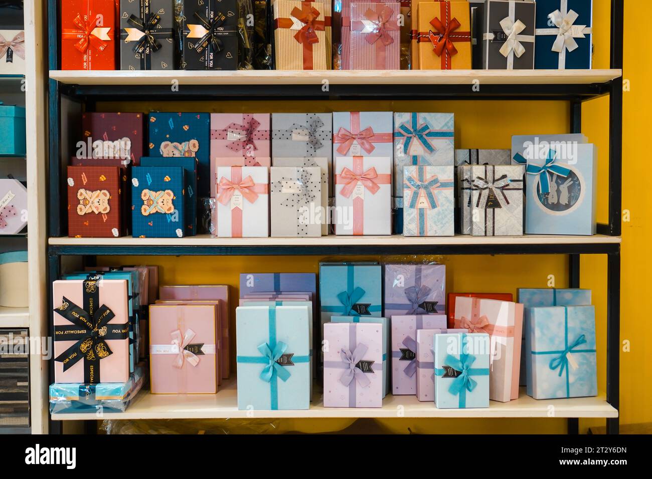 Colorful and patterned gift box stacks arranged on multi-tiered shelves ...