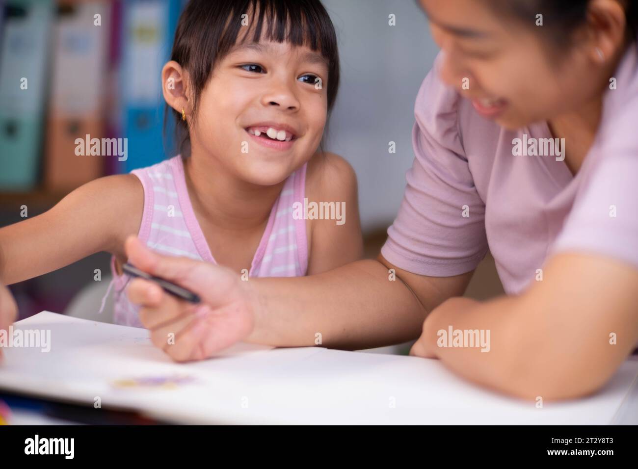 Mother and daughter drawing together with crayons. Adult woman helps ...