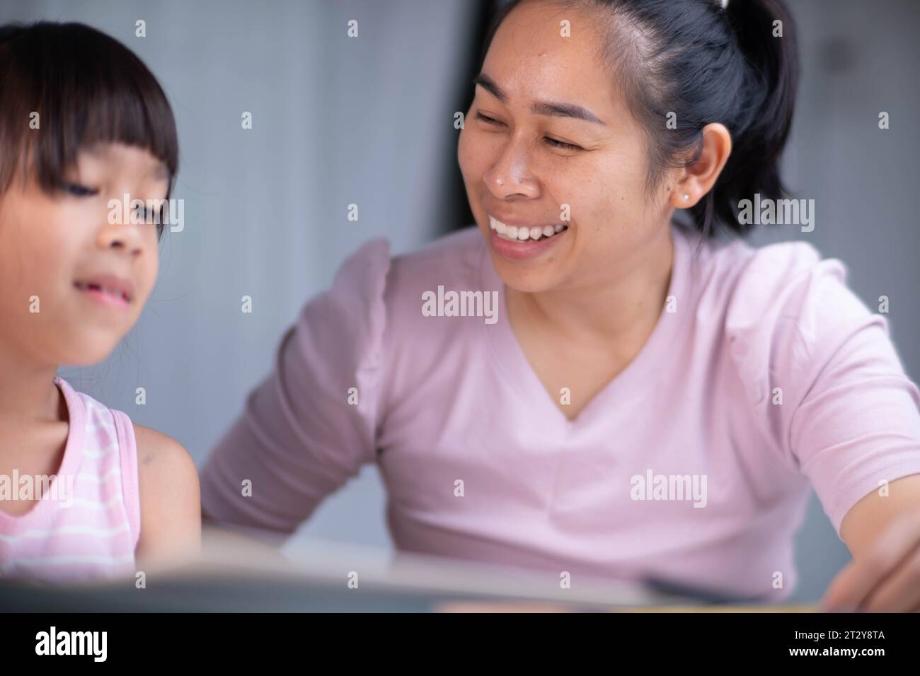 Mother and daughter drawing together with crayons. Adult woman helps girl study or draw together ...