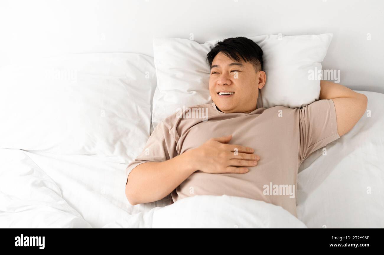 Pleased Middle Aged Asian Man Lying In Bed Stock Photo - Alamy