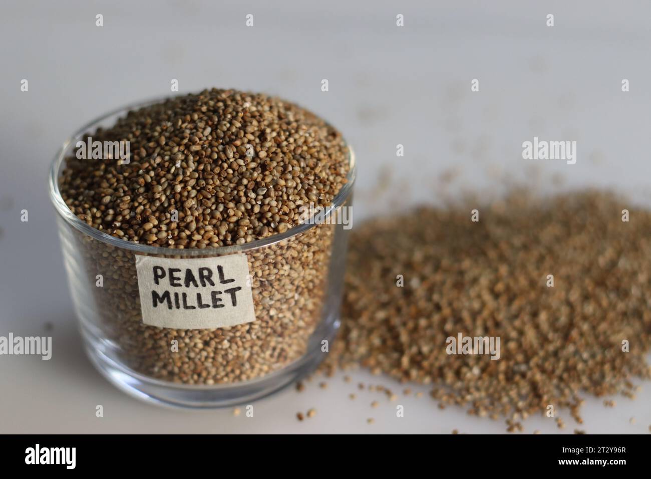 Pearl millet grains in a glass bowl with label on it filled to the brim ...