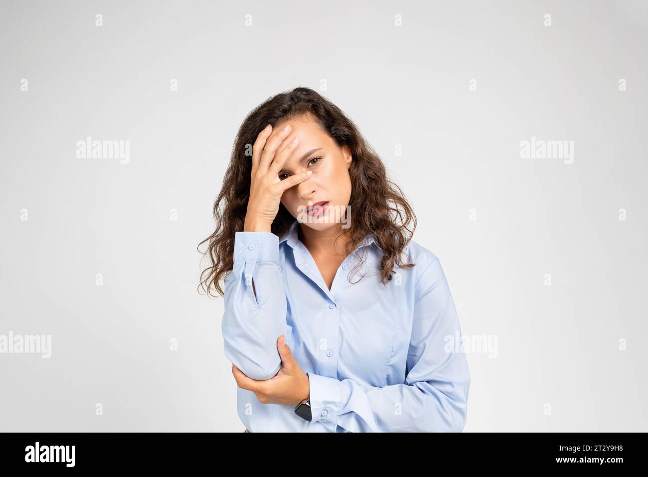Young stressed woman at work, pressing hand to forehead, evident ...