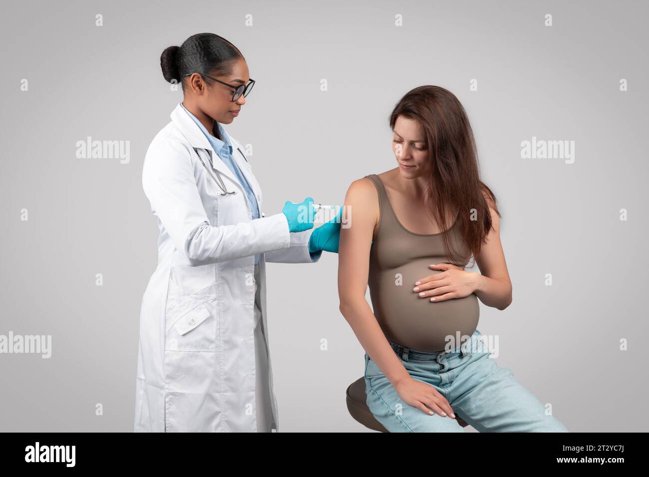 Serious african american lady doctor make injection to pregnant patient ...