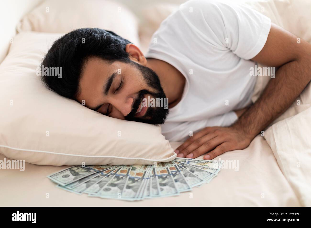 Money Savings. Smiling indian man sleeping with dollar cash under ...
