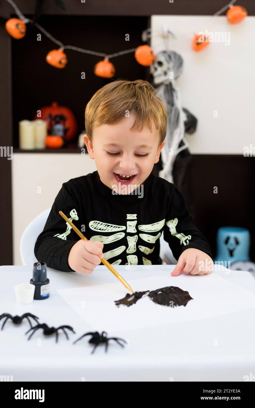 A child dressed as a skeleton shows spider and ghost crafts. Halloween ...