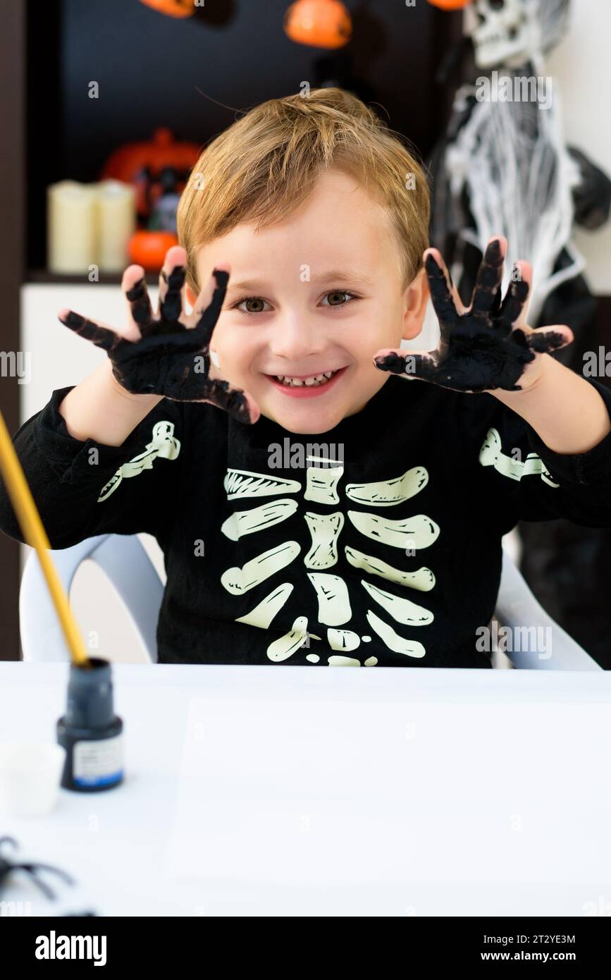 A child dressed as a skeleton shows spider and ghost crafts. Halloween ...