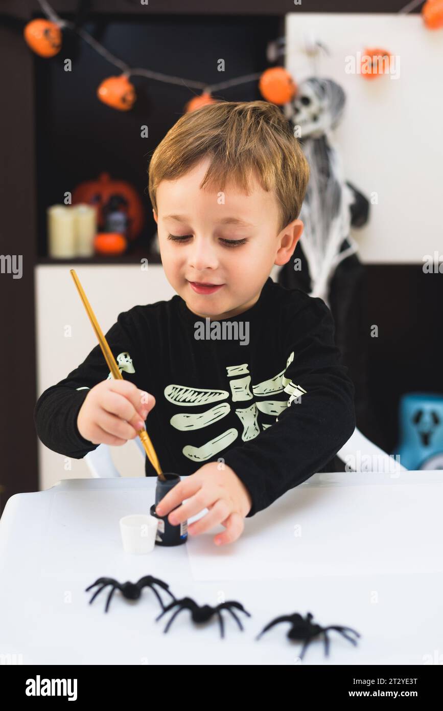 A child dressed as a skeleton shows spider and ghost crafts. Halloween ...