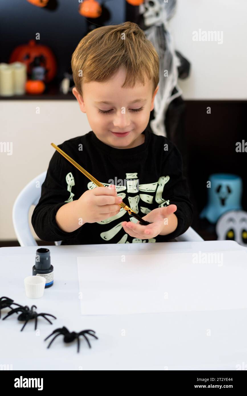 A child dressed as a skeleton shows spider and ghost crafts. Halloween ...