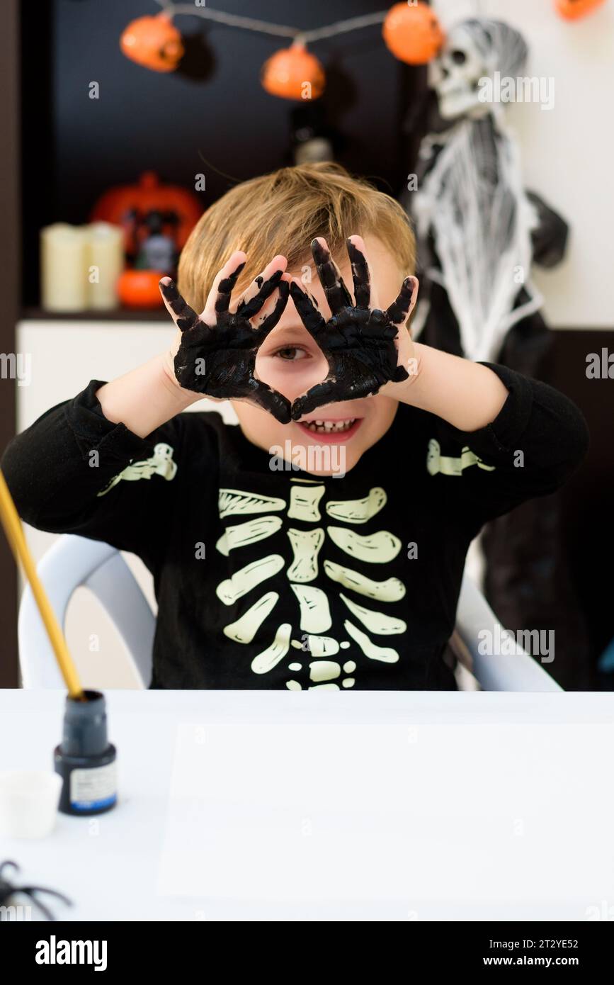 A child dressed as a skeleton shows spider and ghost crafts. Halloween ...