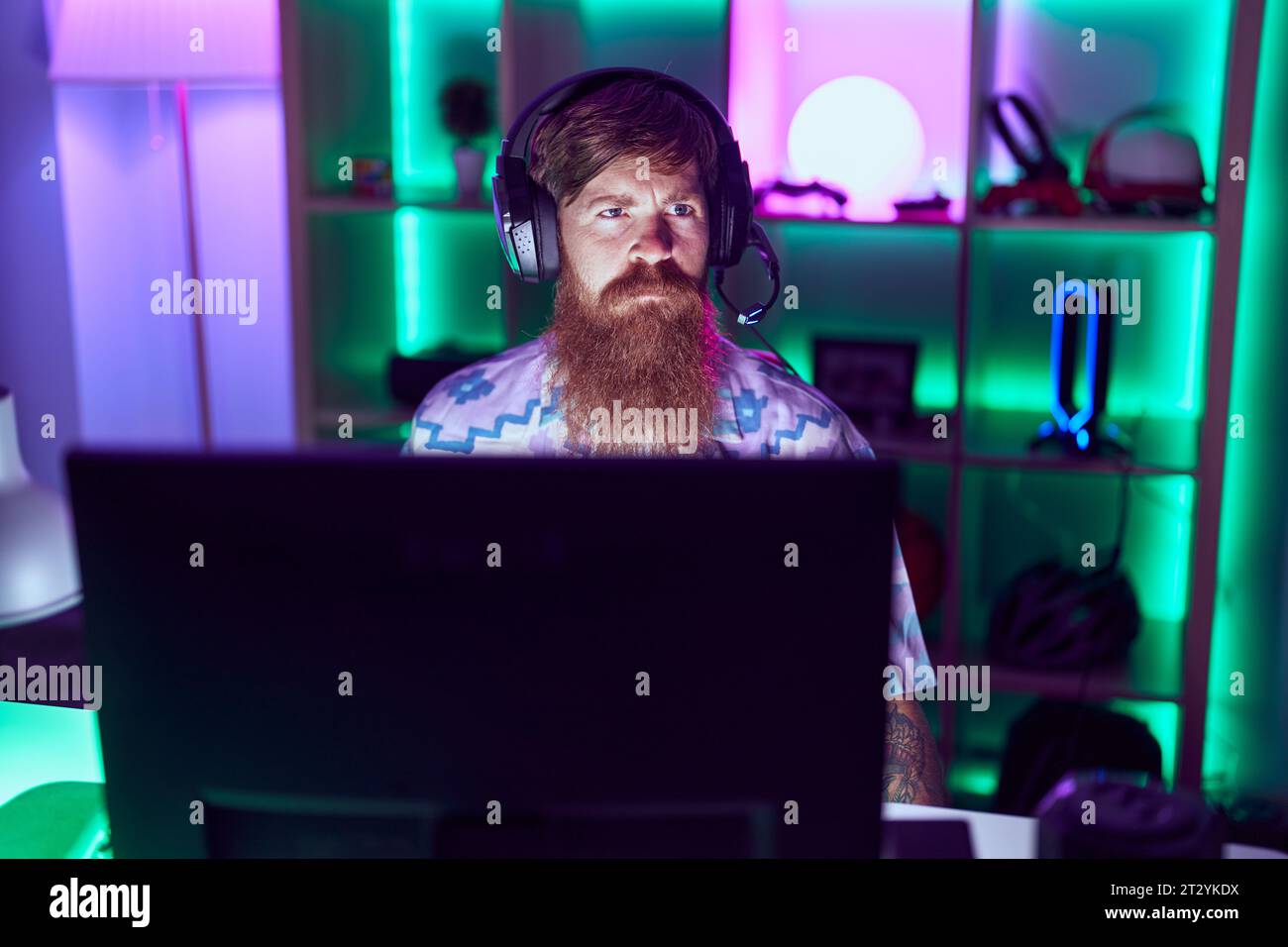 Young redhead man streamer playing video game using computer at gaming ...