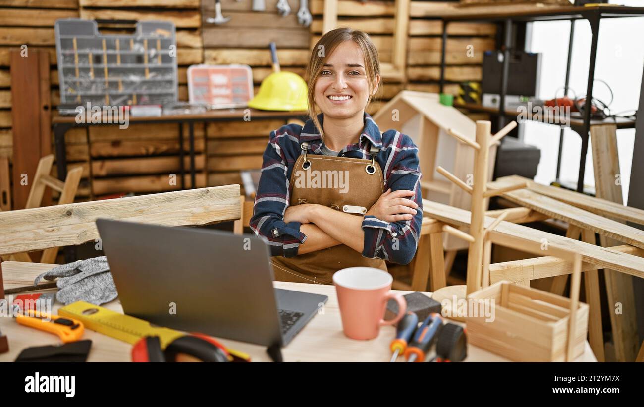Smiling young blonde woman carpenter, arms crossed, joyfully navigating ...