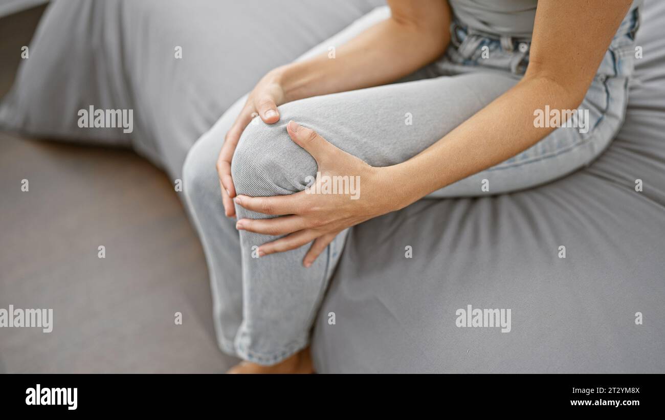 Woman’s hands touching injured knee, expressing agony whilst awake in ...
