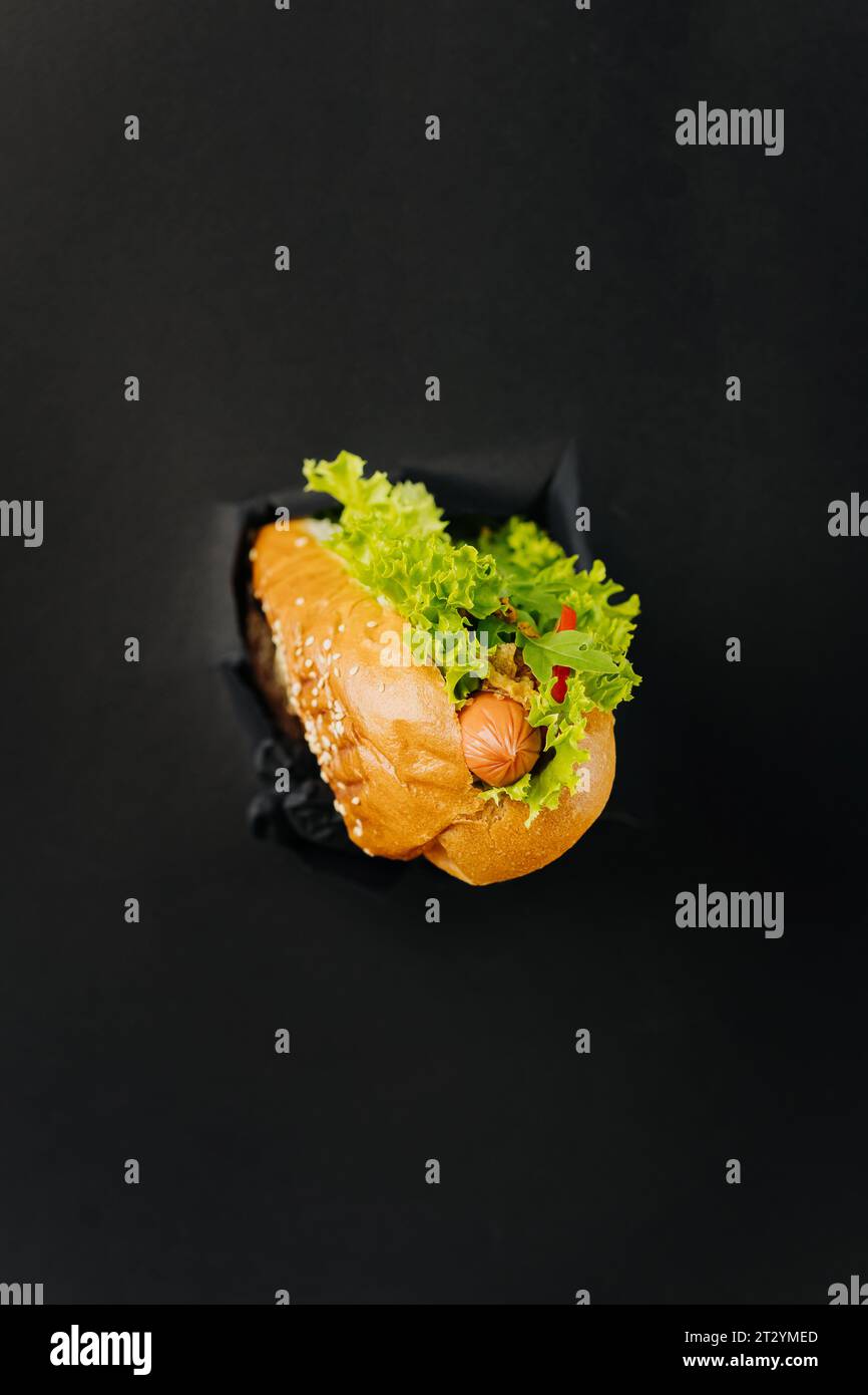 Fresh hot dog sticks out through torn holes in paper background. Street ...