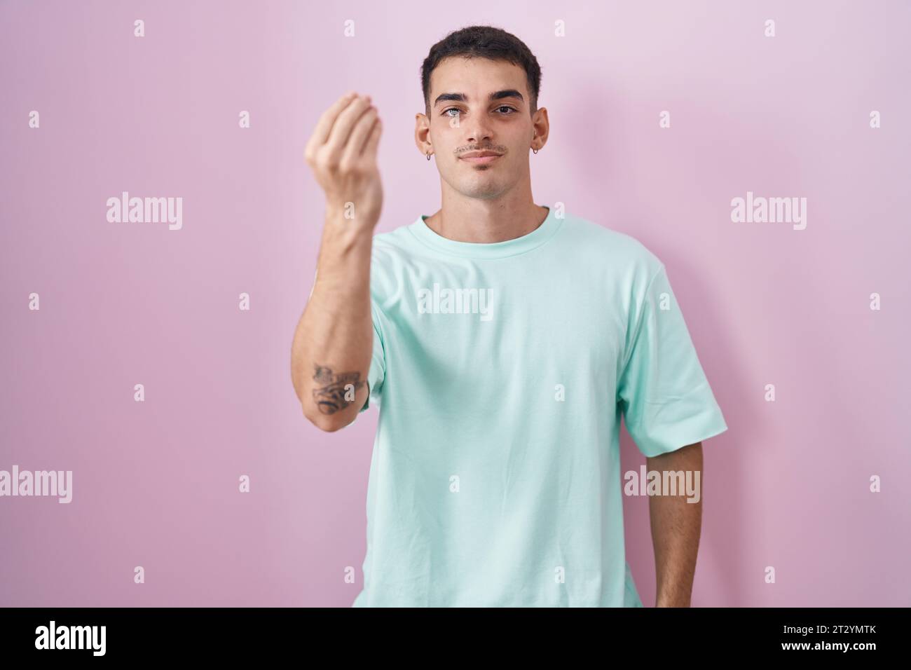 Handsome hispanic man standing over pink background doing italian ...