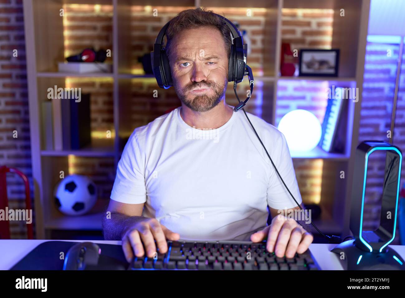 Middle age man with beard playing video games wearing headphones ...