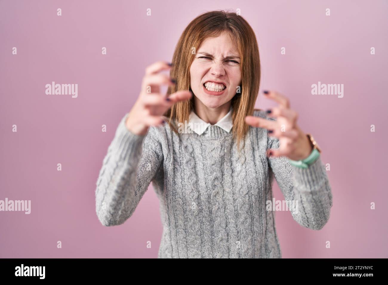 Beautiful woman standing over pink background shouting frustrated with ...