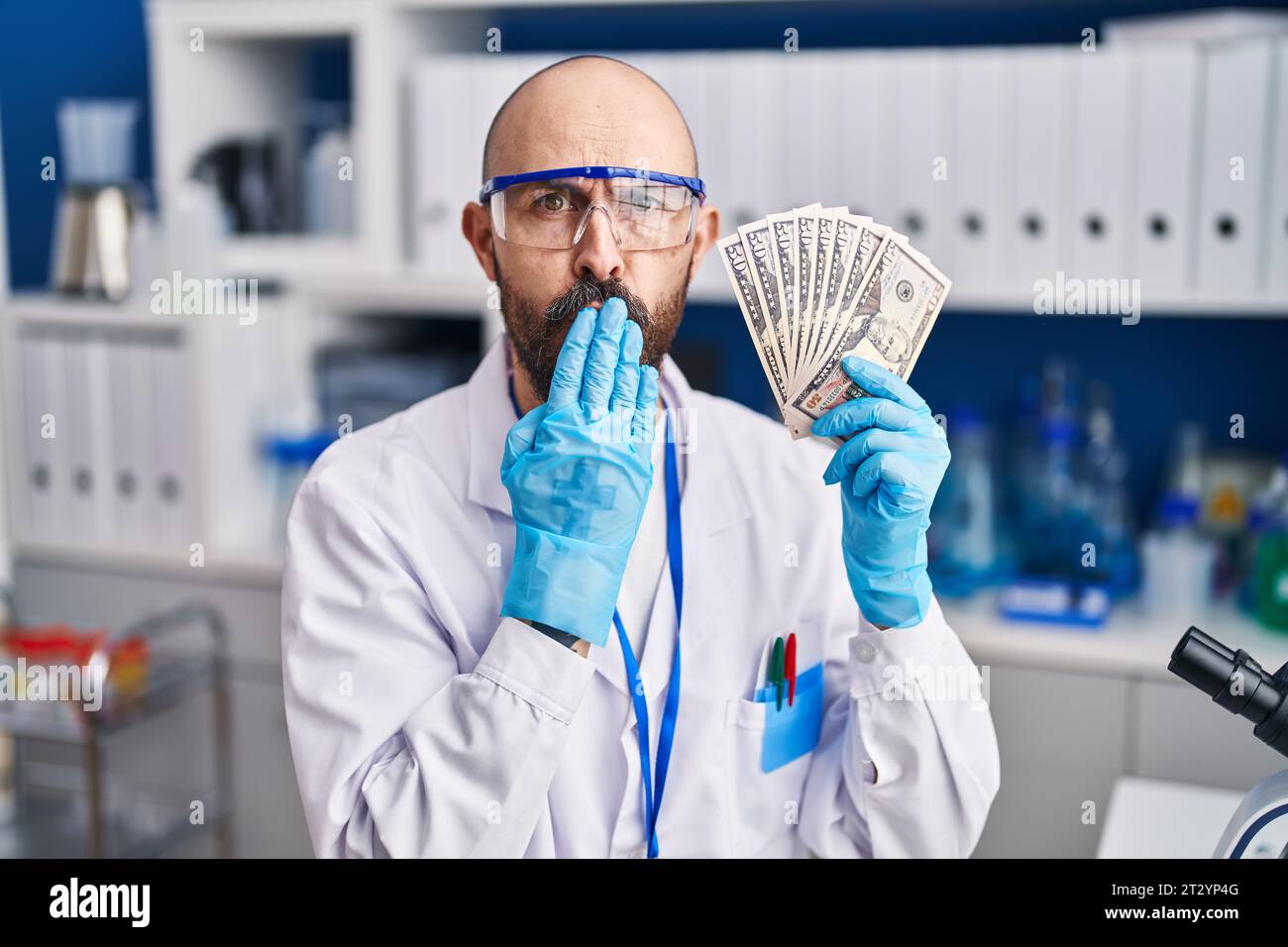 Young hispanic man working at scientist laboratory holding money ...