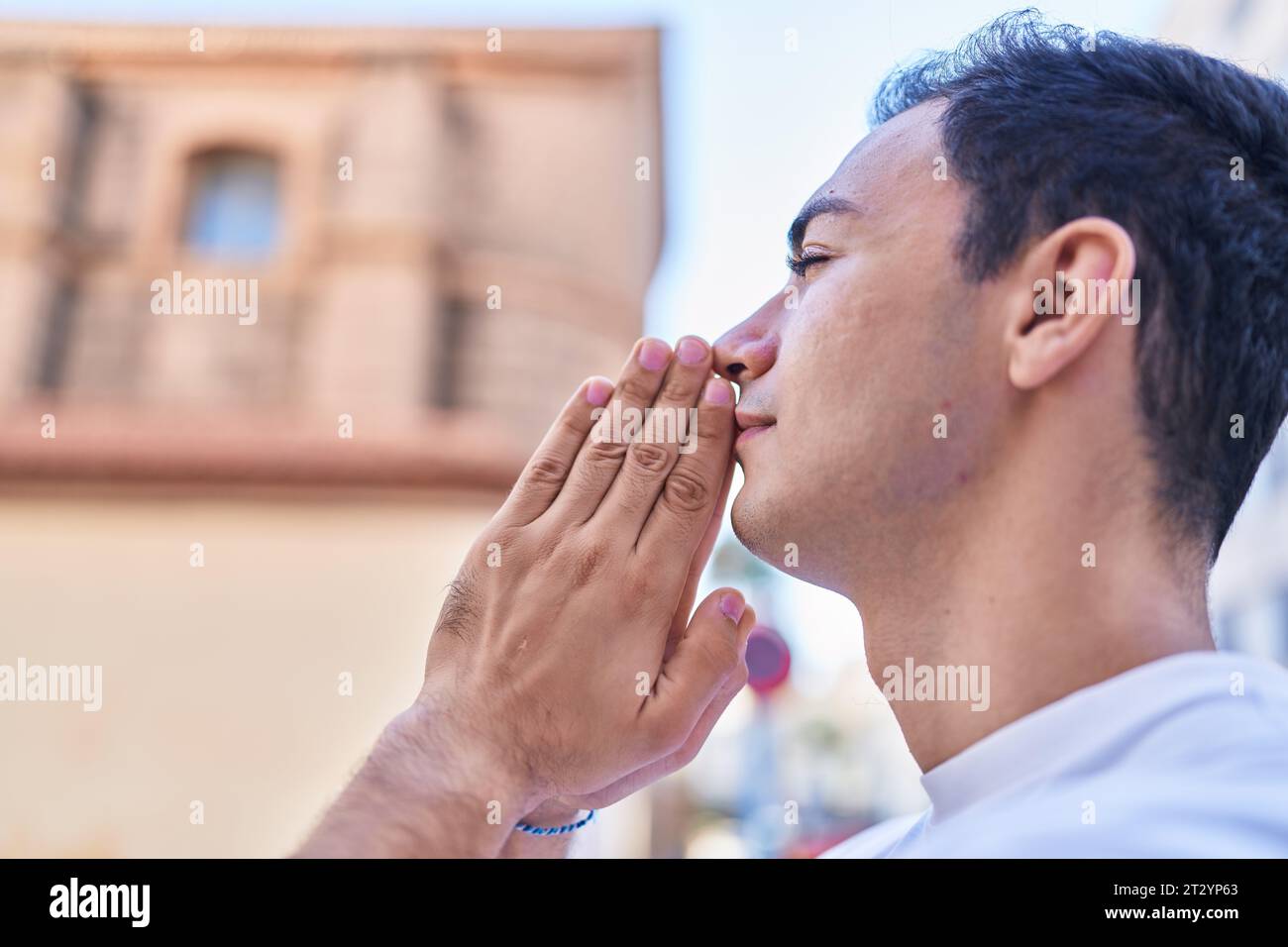 Young hispanic man praying with closed eyes at street Stock Photo - Alamy