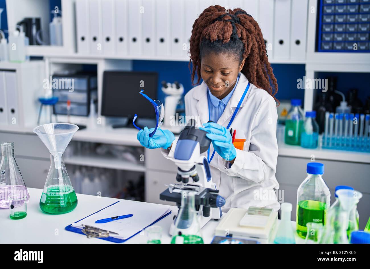 African american woman scientist smiling confident using microscope at laboratory Stock Photo ...