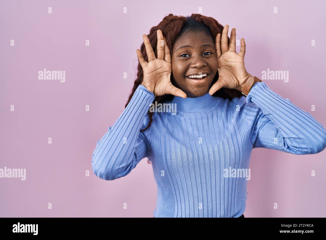 African woman standing over pink background smiling cheerful playing ...