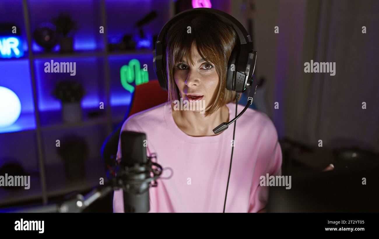 Beautiful young hispanic female streamer engrossed in intense gaming ...