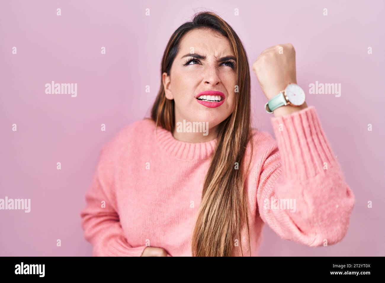 Young hispanic woman standing over pink background angry and mad ...