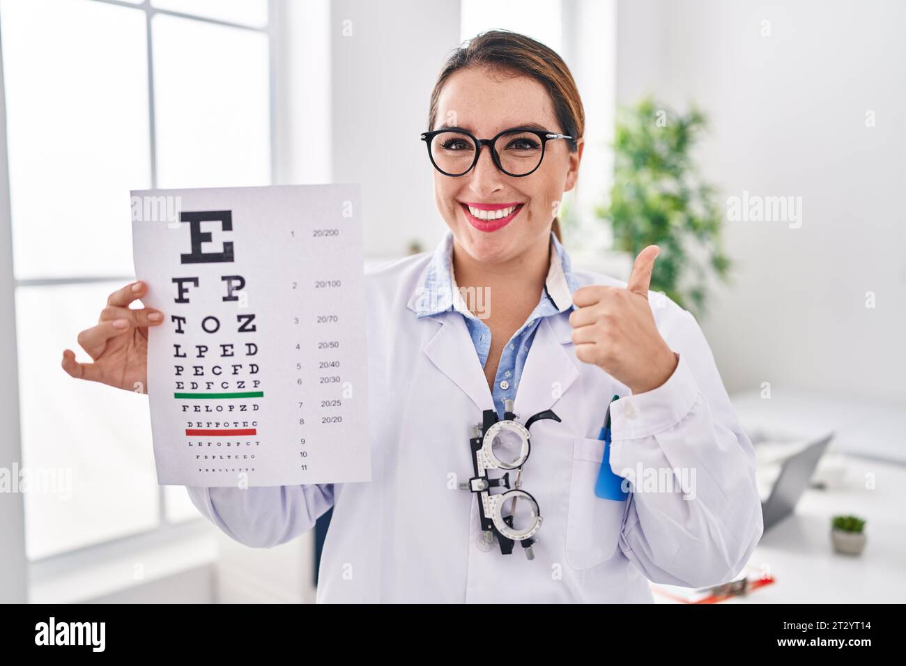 Young hispanic optician woman holding medical exam smiling happy and ...