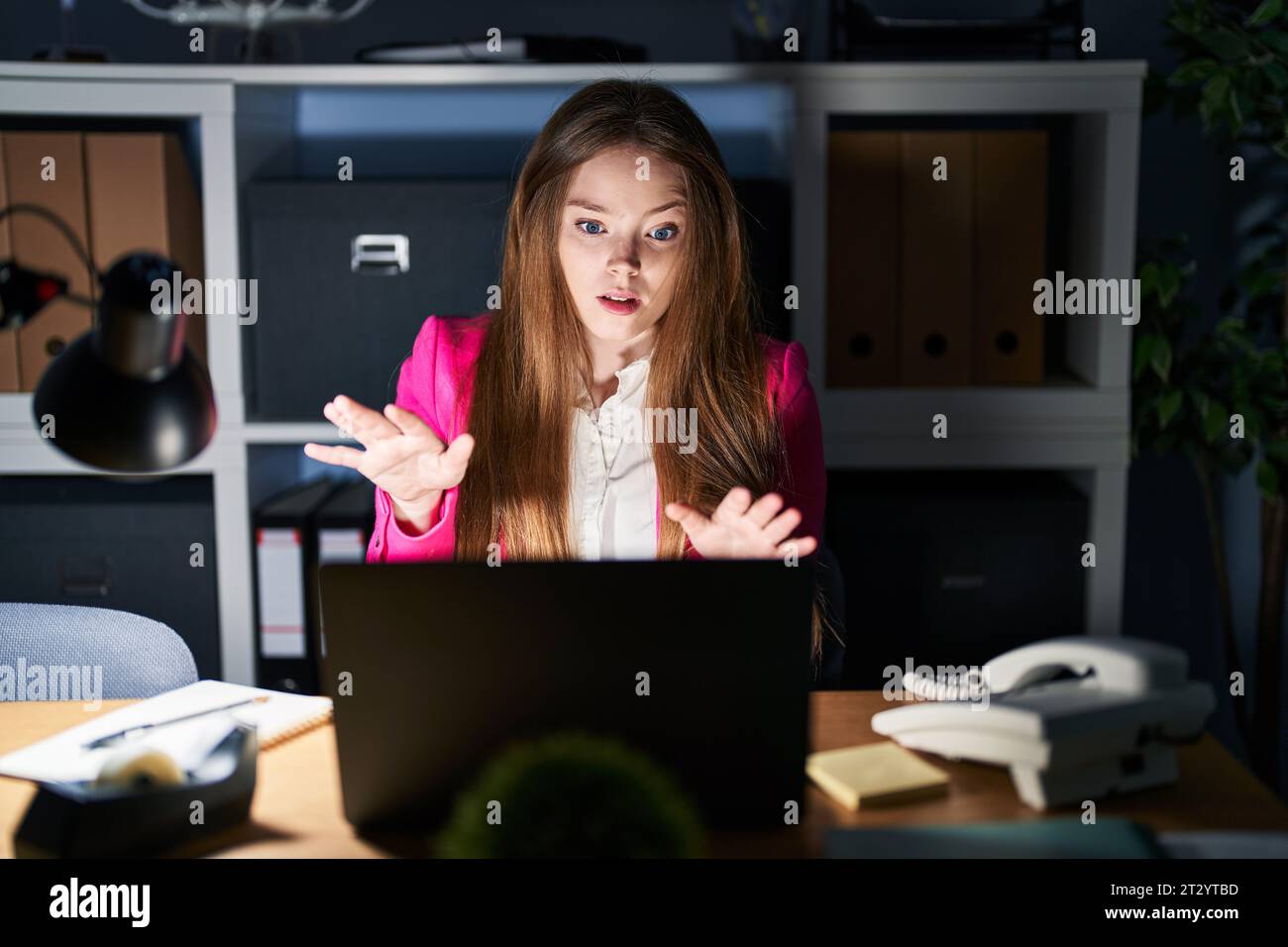 Young caucasian woman working at the office at night afraid and ...