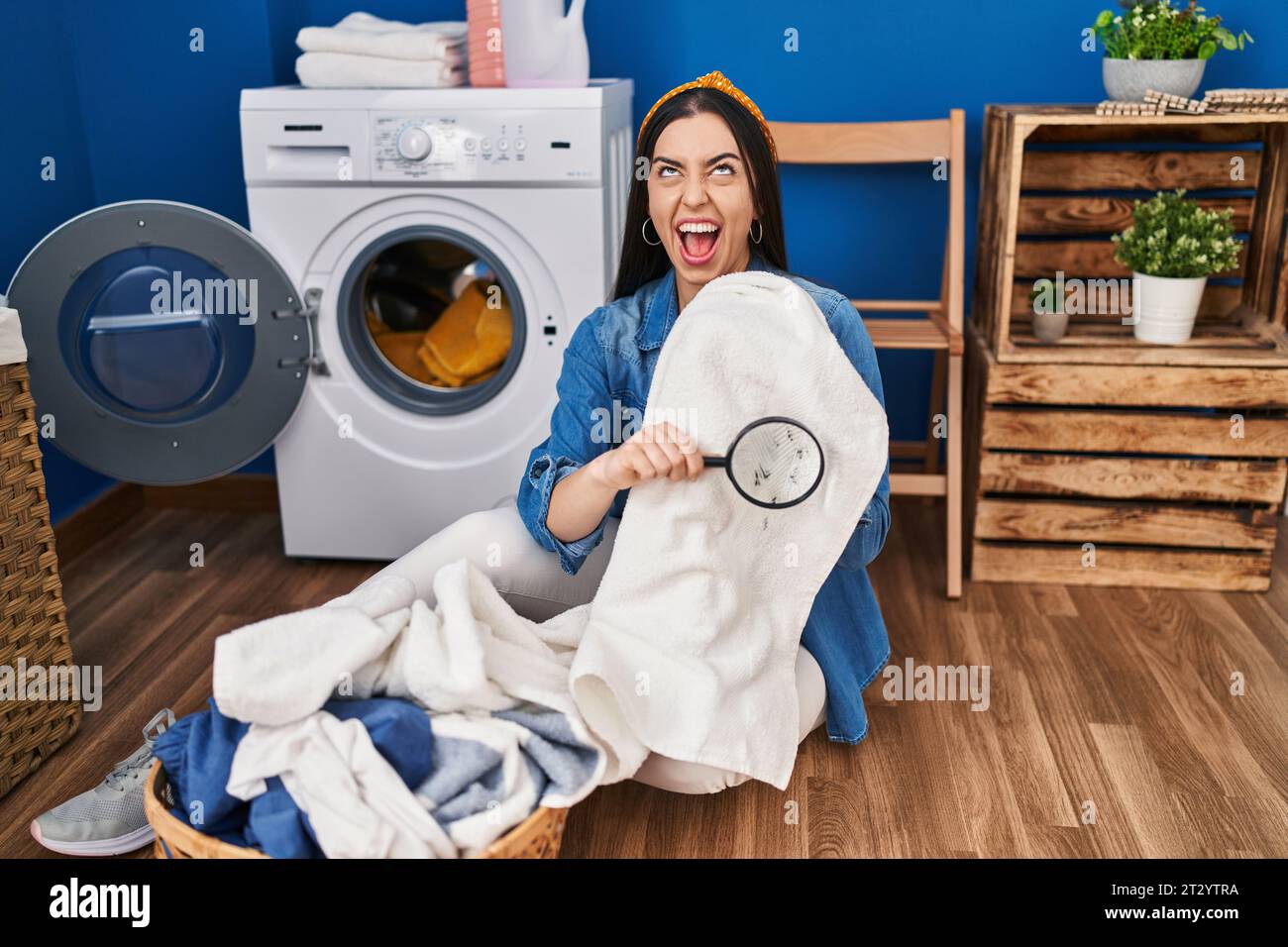 Hispanic woman holding magnifying glass looking for stain at clothes ...