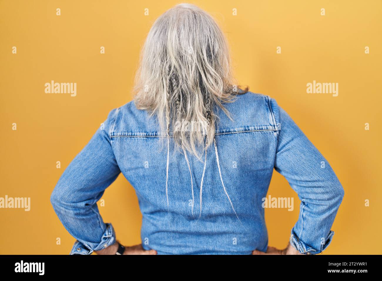 Middle age man with grey hair standing over yellow background standing ...