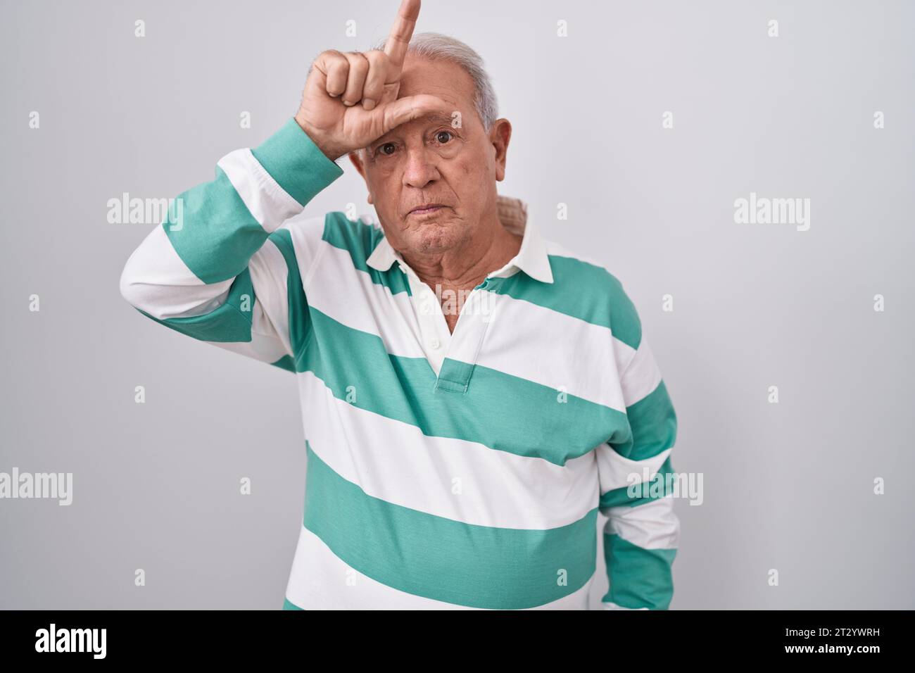 Senior man with grey hair standing over white background making fun of ...
