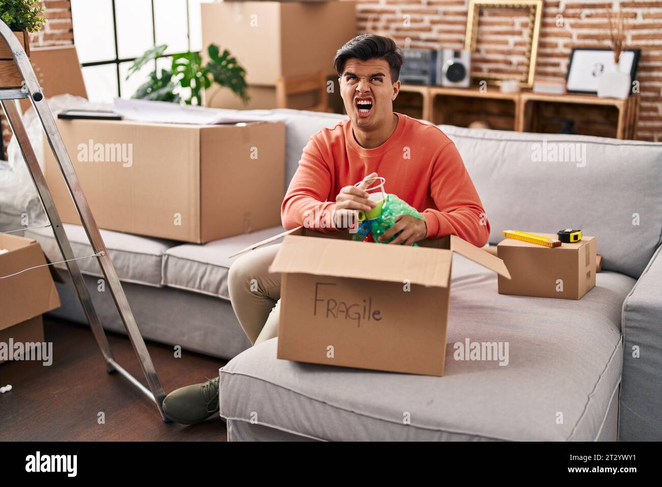 Hispanic man moving to a new home unpacking angry and mad screaming ...