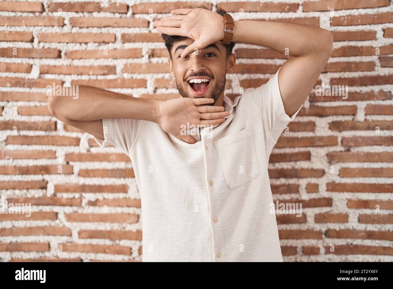 Arab man with beard standing over bricks wall background smiling ...