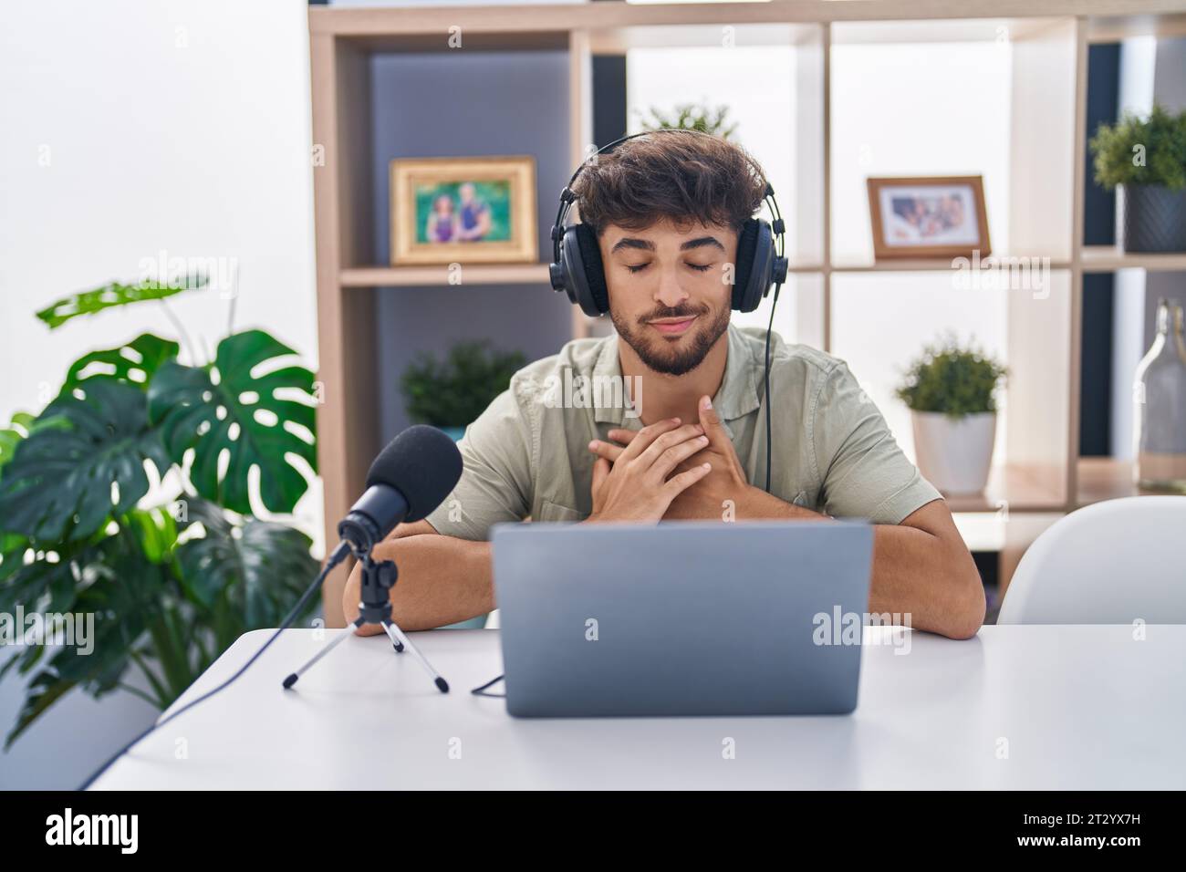 Arab man with beard working at the radio smiling with hands on chest ...