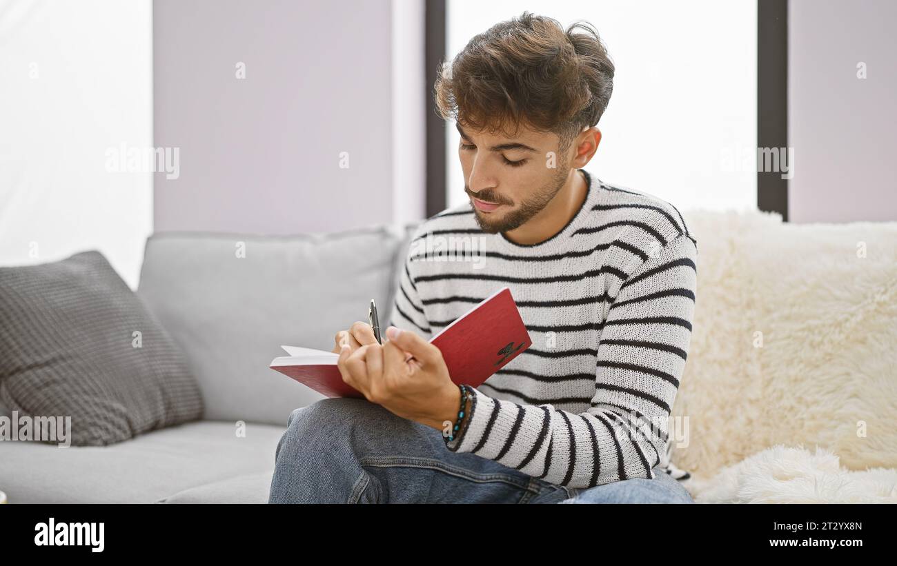 Smart young arab man, comfortably seated on sofa, intensely studying ...