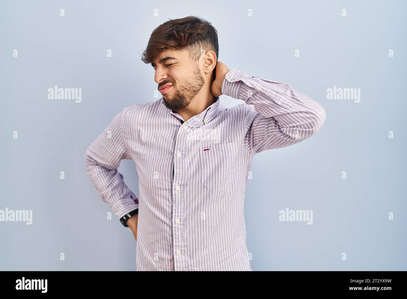 Arab man with beard standing over blue background suffering of neck ...