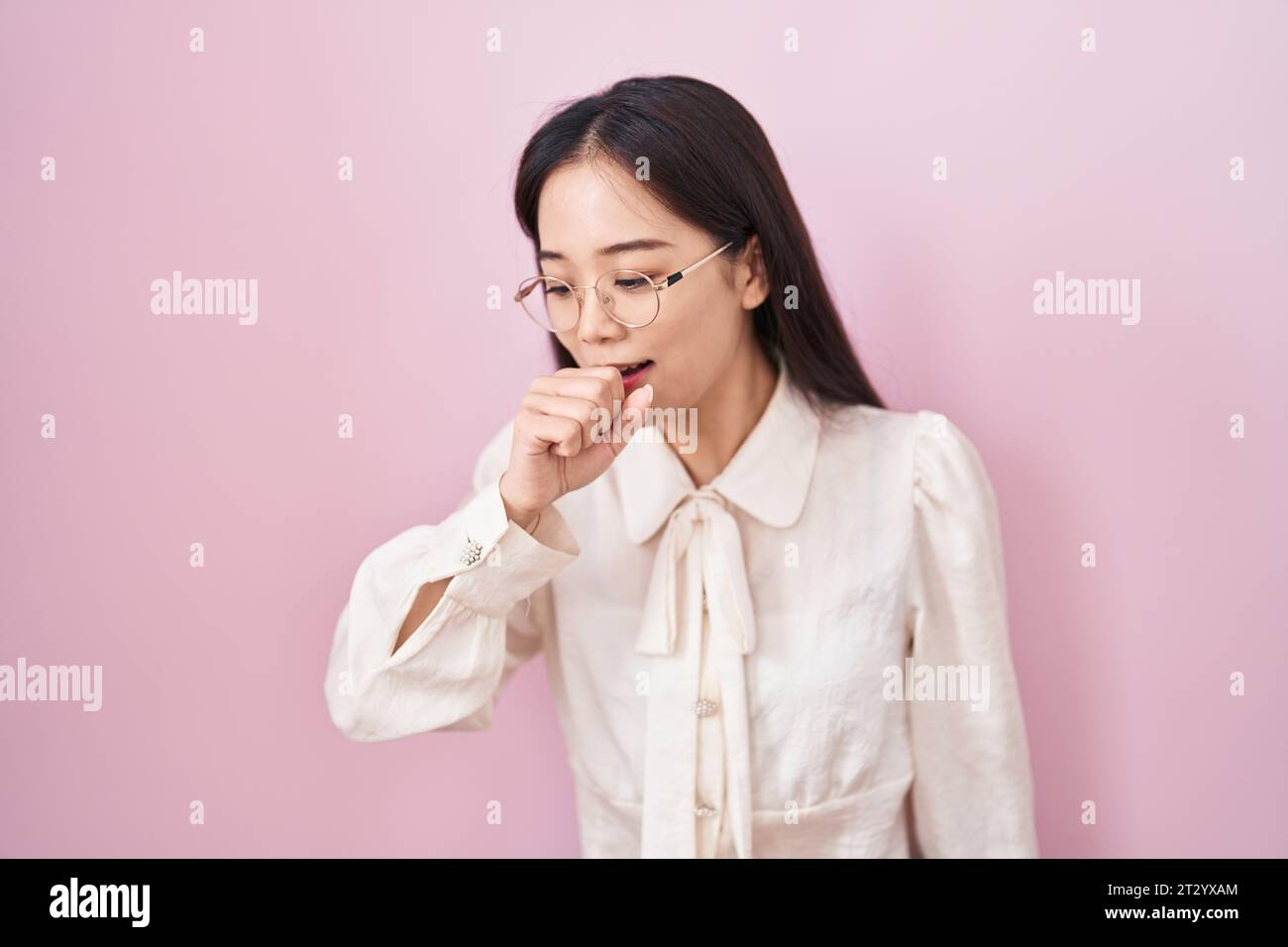 Young chinese woman standing over pink background feeling unwell and ...