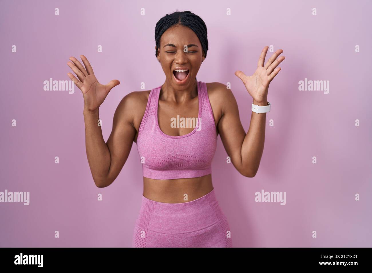 African american woman with braids wearing sportswear over pink ...