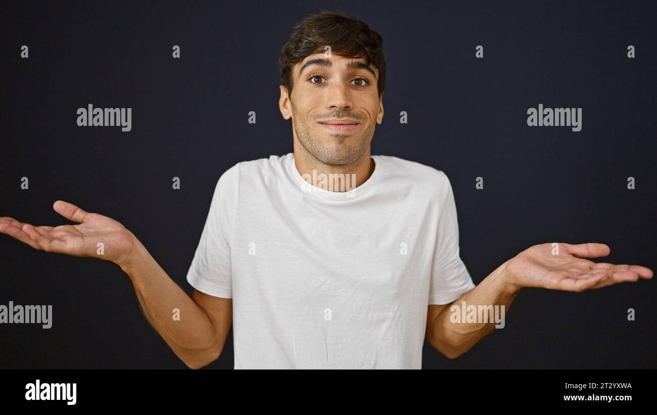 Confused young hispanic man cluelessly standing alone against isolated ...